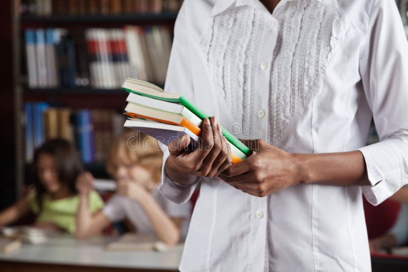Librarian Holding Books while Standing in Library Stock Photo - Image ...