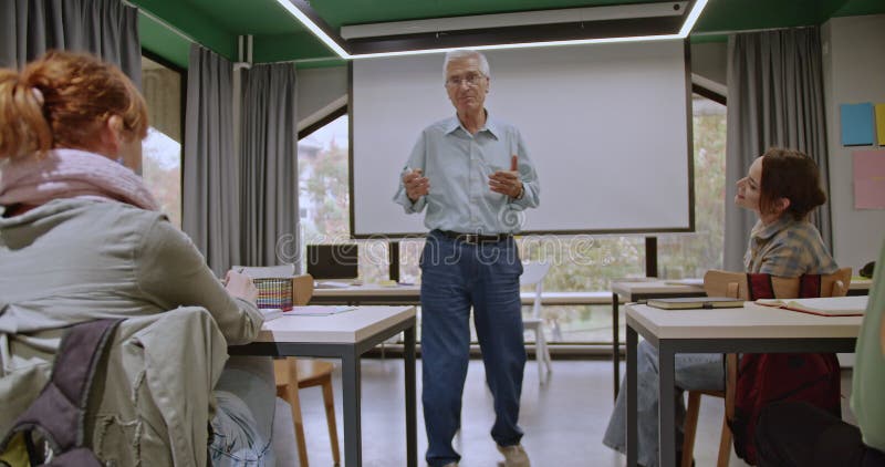 Focused Students Studying in a Library with an Elderly Professor ...