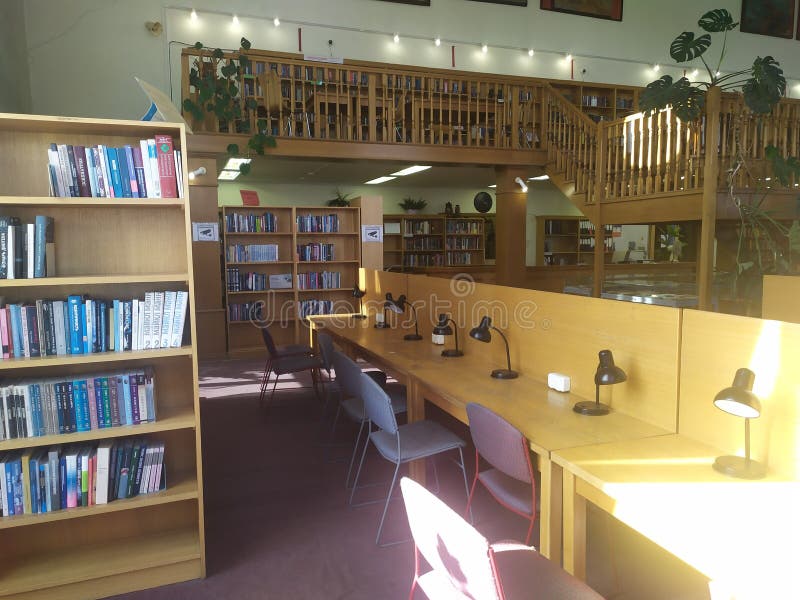 The Library at the University, Bookcases and Tables with Lamps, Chairs, and a Second Floor Above ...