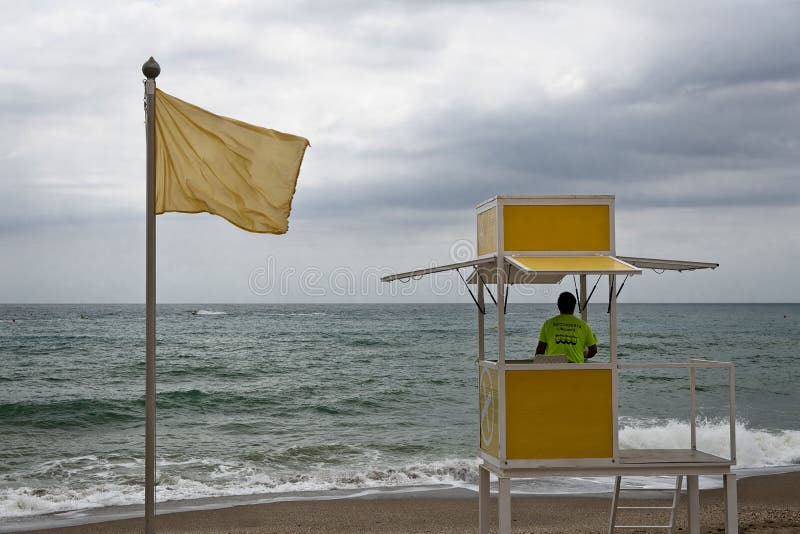 Lifeguard on a Lifeguard Tower Watching on a Beach with Yellow Caution ...