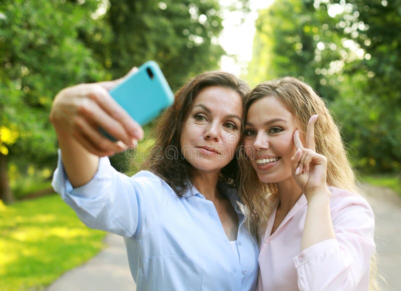 Mature Mother And Adult Daughter Are Doing Selfie By Mobile Phone In