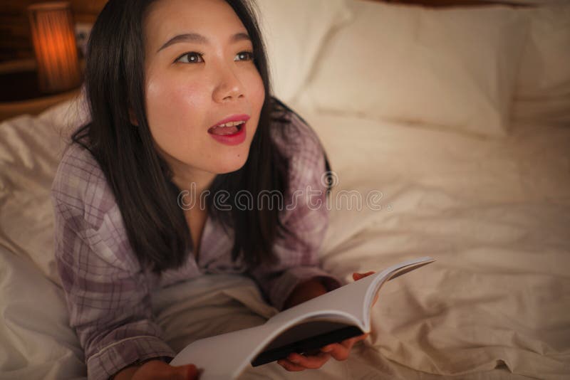 Young Beautiful And Sweet Asian Chinese Woman In Bed Reading Book Novel