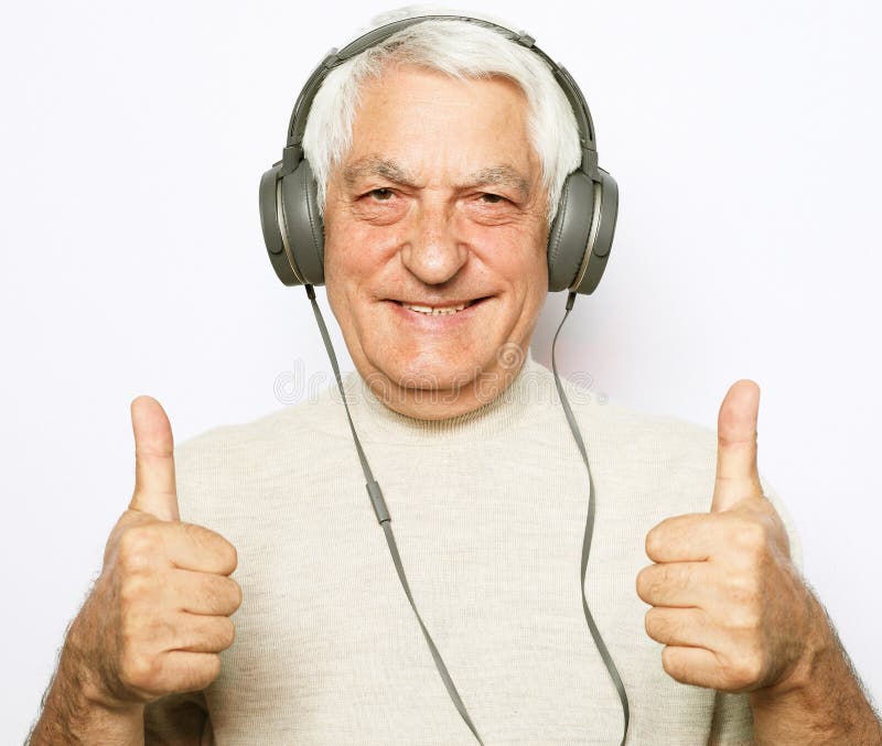 Handsome Old Man In Casual Wear And Headphones Is Listening To Music On