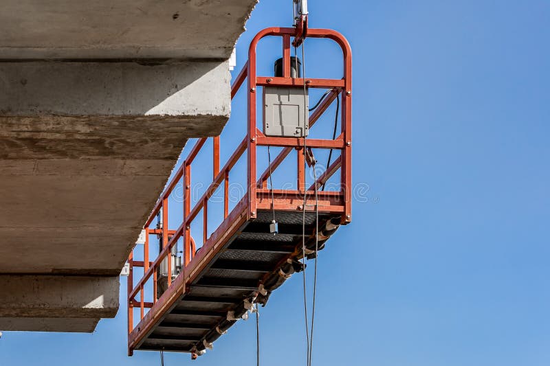 A Lifting Cradle at a Construction Site Hangs on the Monolithic Frame ...