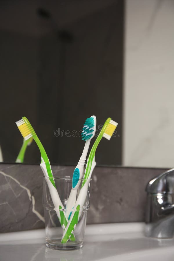 Light Blue and Green Toothbrushes in Glass Holder on Washbasin Stock ...