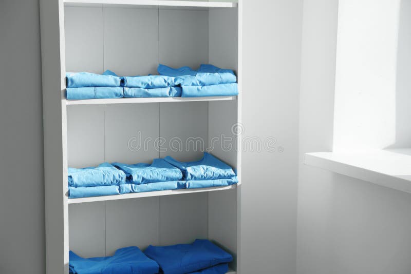 Light Blue Medical Uniforms on White Rack Indoors, Space for Text Stock ...