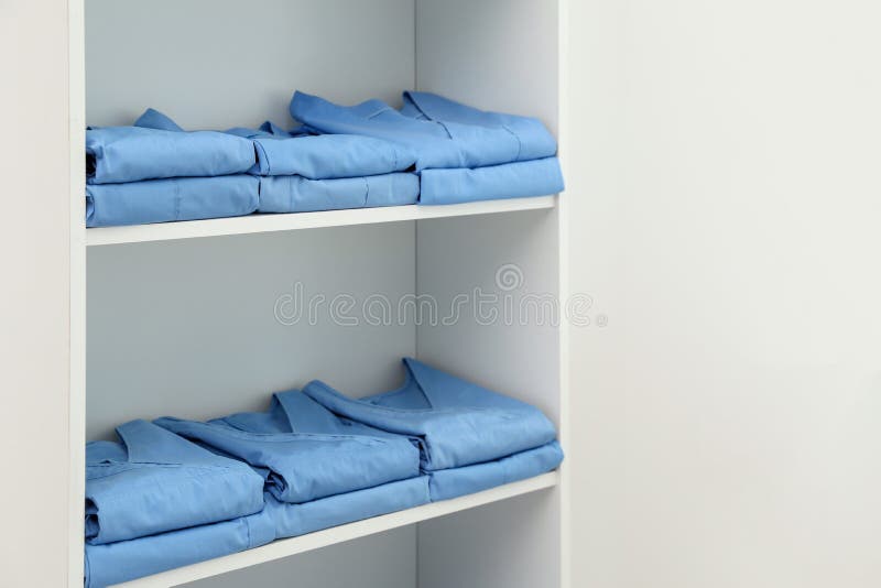 Light Blue Medical Uniforms on White Rack Indoors, Space for Text Stock ...