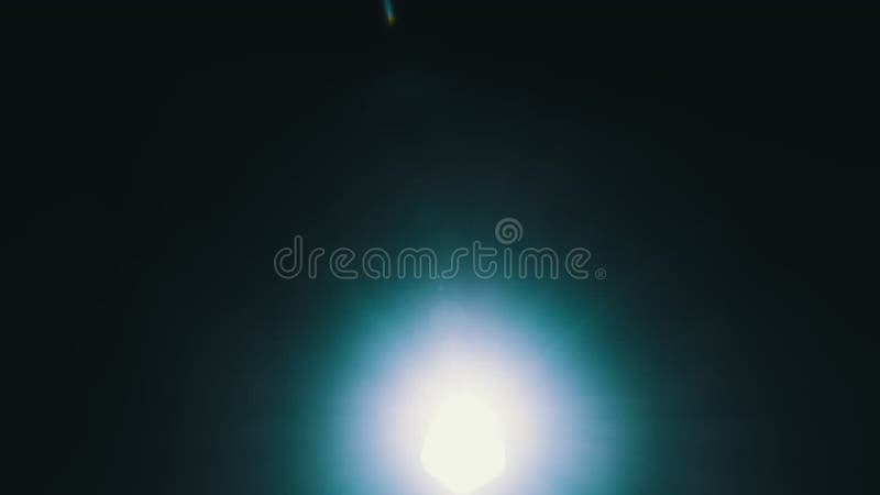 The Light of a Bright Flashlight Directed at the Camera Moves from Side ...