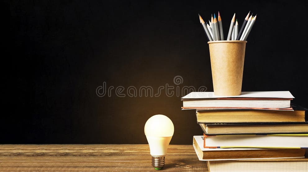 Light Bulb is Lit Up on a Table with a Stack of Books and Pencils Stock Image - Image of light ...