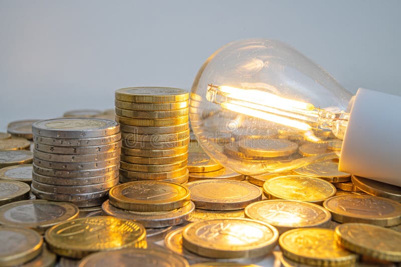 Light Bulb Turned on, with Coins Around. Energy Costs. Stock Photo ...