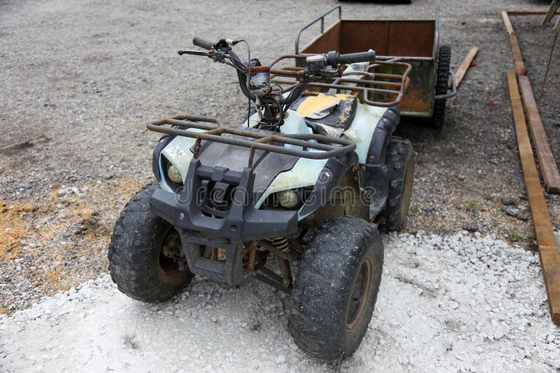 A Light-gray ATV, Complete with a Rusty Utility Trailer, Sits on a ...