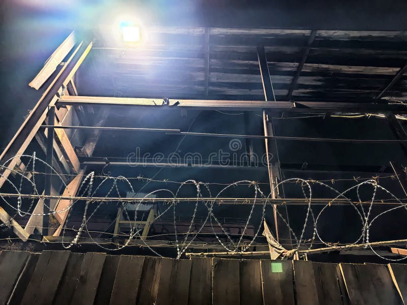 Light Illuminates a Dilapidated Warehouse with Barbed Wire in an Urban ...