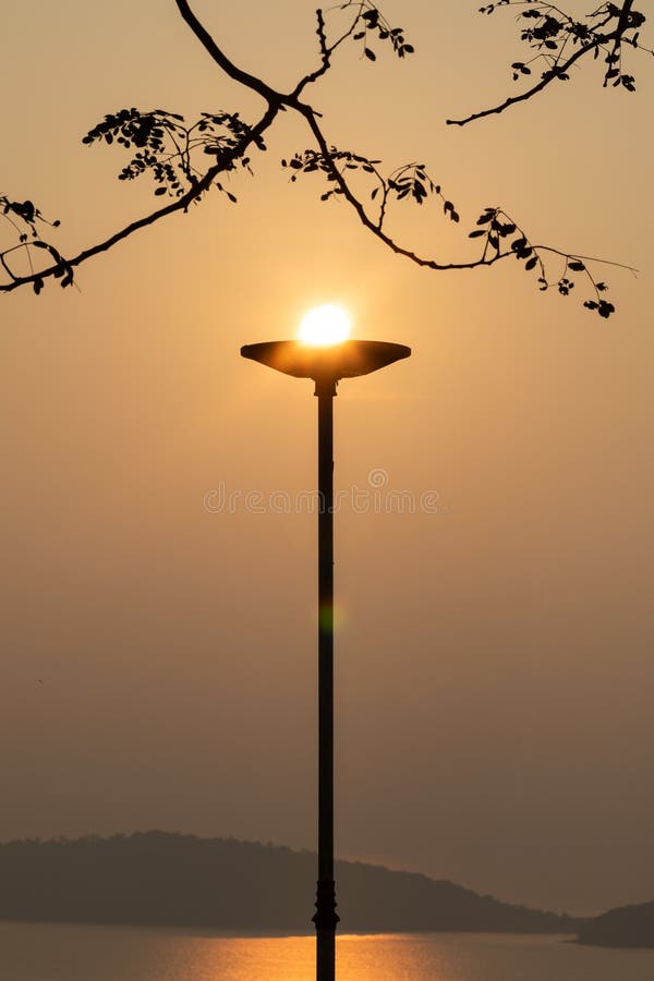 The Light Lamp Pole with Bright Sun on the Top at Sunrise Over the Sea ...