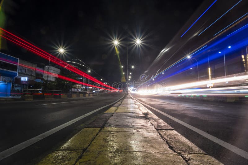 Light Trails of Passing Vehicles in the Middle of the Sidewalk at Night ...