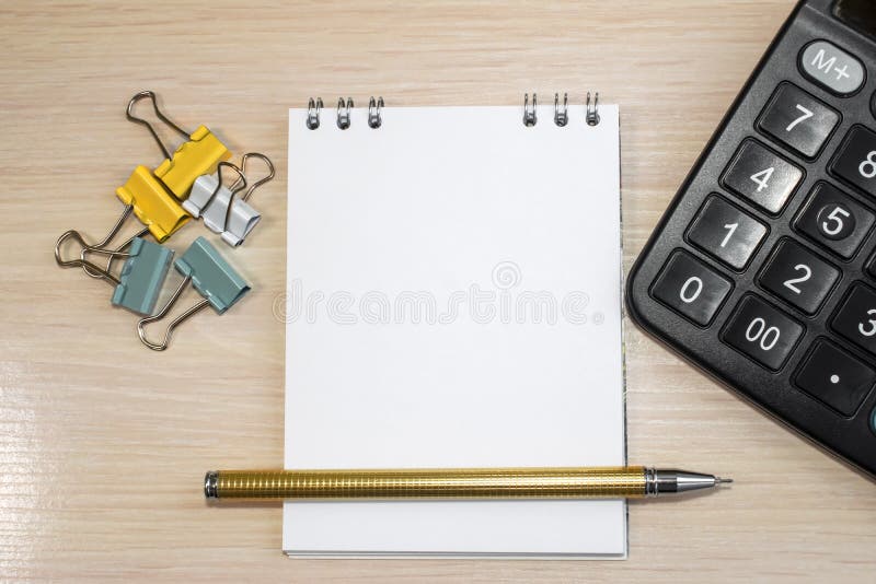 On the Light Wooden Table is an Open Notebook with a Pen. Calculator ... On the Light Wooden Table is an Open Notebook with a Pen. Calculator ...