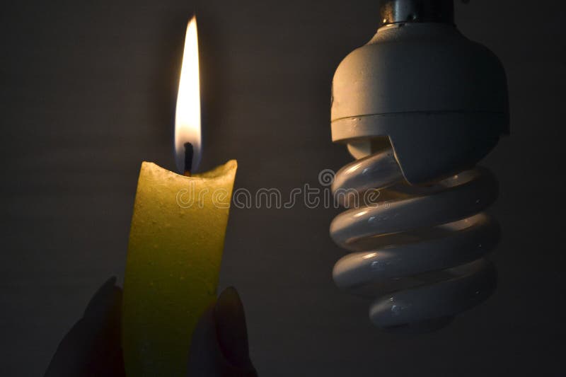 A Lighted Candle Shines Near a Light Bulb in the Dark Stock Photo ...