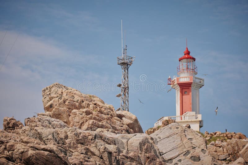 Lighthouse Atop a Rocky Cliff, Illuminated by a Bright Beam of Light ...