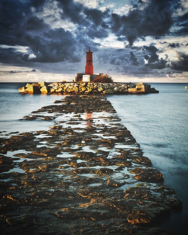 Lighthouse in a Cloudy Sunrise in Long Exposure Stock Image - Image of ...