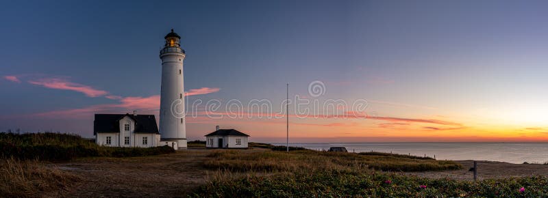The Lighthouse is Lit Up at Night on the Beach at Sunset Editorial ...