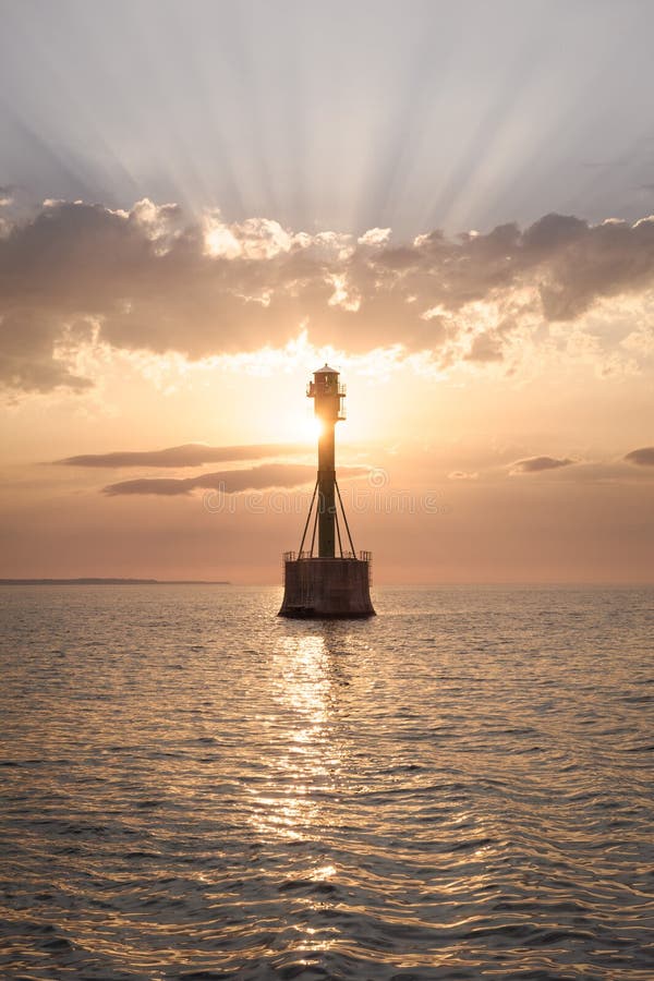 Lighthouse in the Ocean at Sunset with Sun Rays Stock Photo - Image of ...