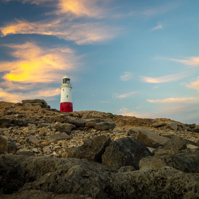 Lighthouse on a Rocky Coast Under a Blue Cloudy Sky Stock Photo - Image ...