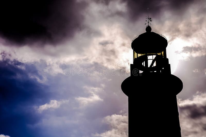 A Lighthouse is Silhouetted Against a Cloudy Sky Stock Image - Image of ...