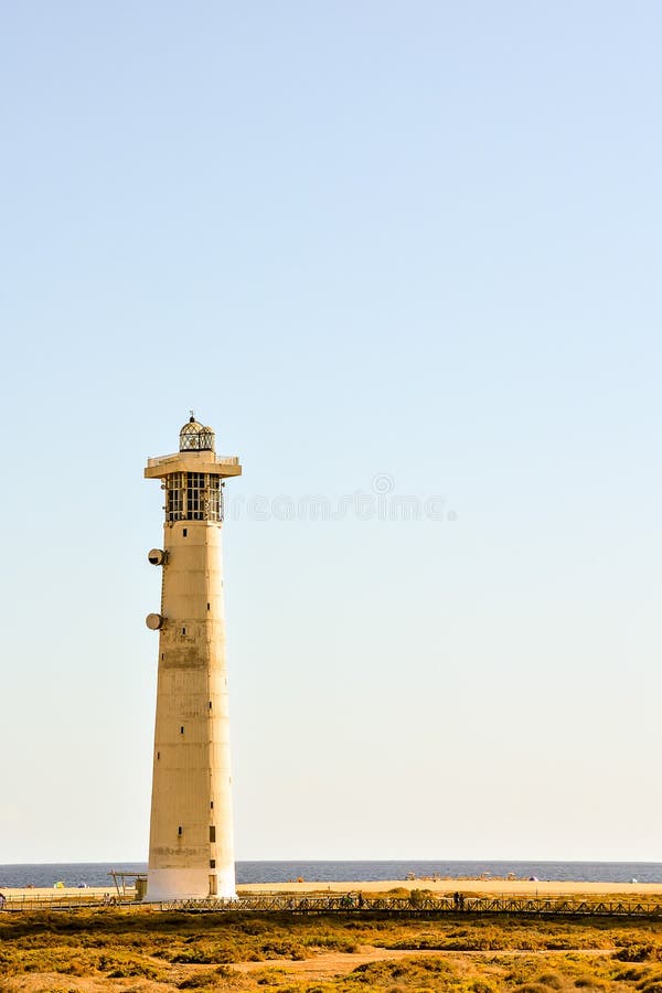 A Lighthouse is Standing on a Beach with a Clear Blue Sky Above it ...
