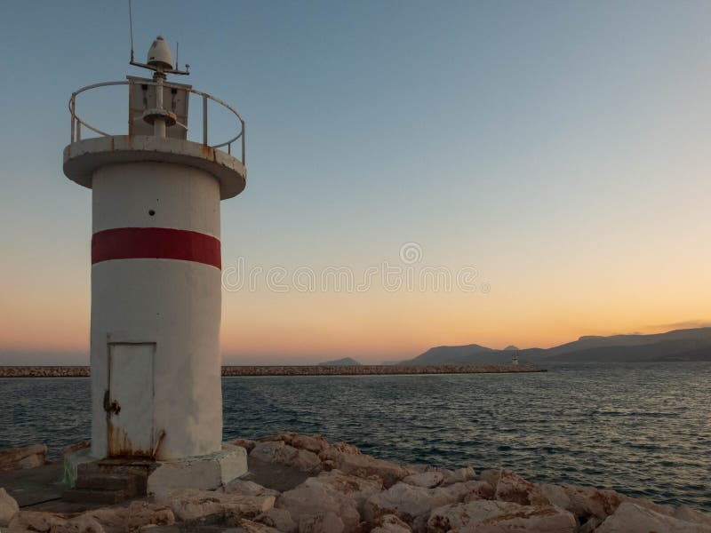 Lighthouse on the Stone Pier, Sea Harbor and Hills at the Sunset Stock ...