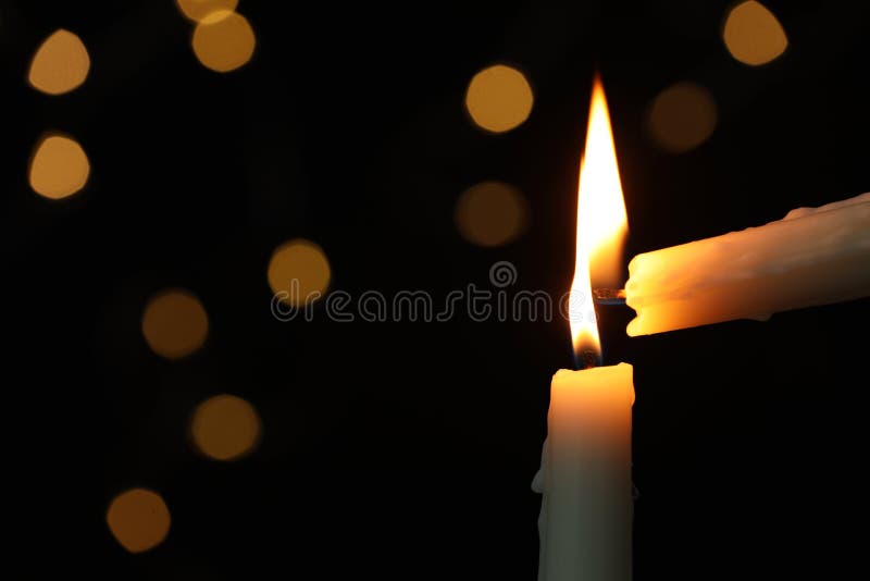 Lighting Candle from Another One Against Blurred Lights in Darkness ...