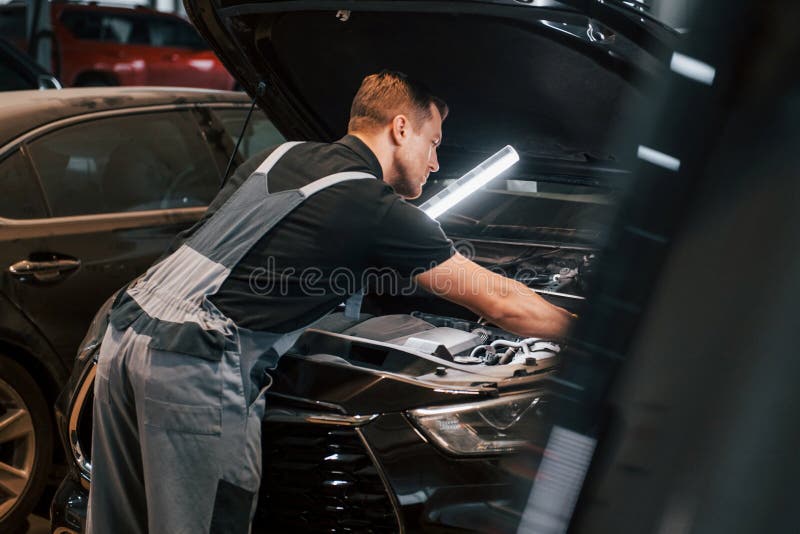 With Lighting Equipment. Man in Uniform is Working in the Auto Service ...