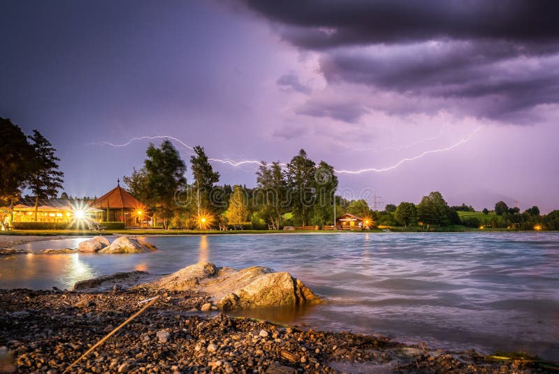 A Lightning Bolt is Seen Above the Water and Rocks on the Shore Stock ...