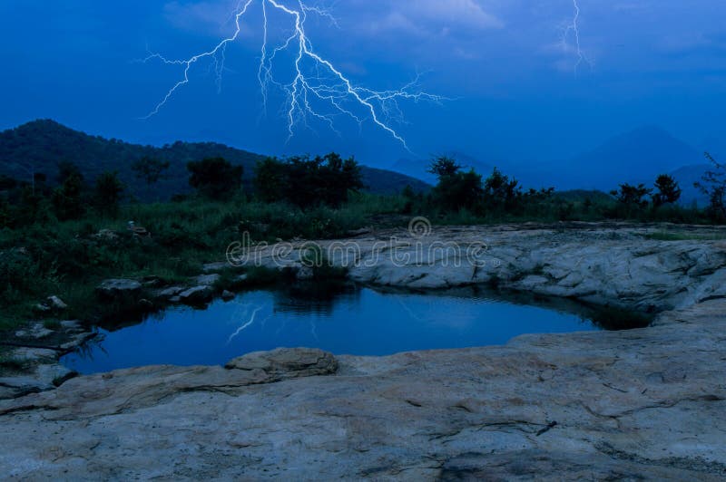 Lightning Strikes Over a Dark Forest with Reflection on Water Stock ...