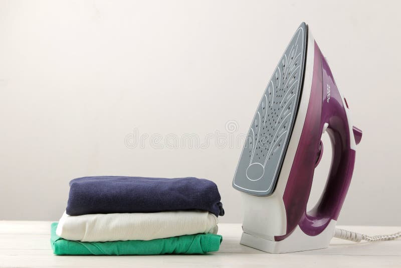 Iron and a Stack of Colored Clothes on a White Background. Ironing of ...