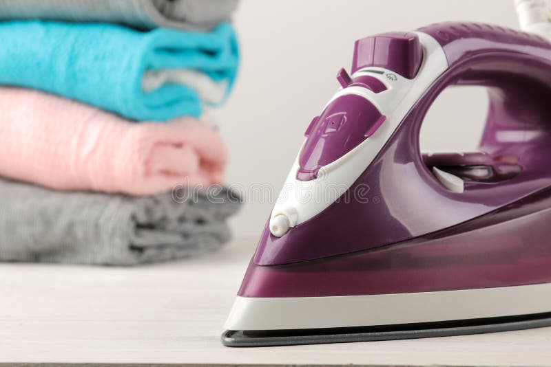 Iron and a Stack of Colored Clothes on a White Background. Ironing of ...