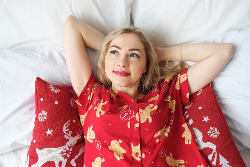 Linda Loira De Pijama Vermelho Deita Se Na Cama Sorri E Olha Para A Janela Imagem De Stock
