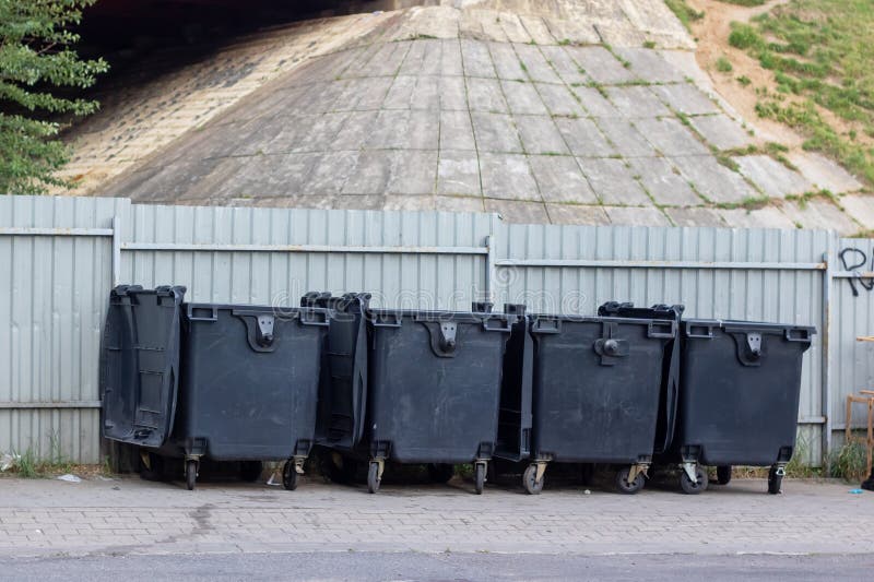A Line of Black Trash Bins is Arranged in Front of a Barrier Stock ...