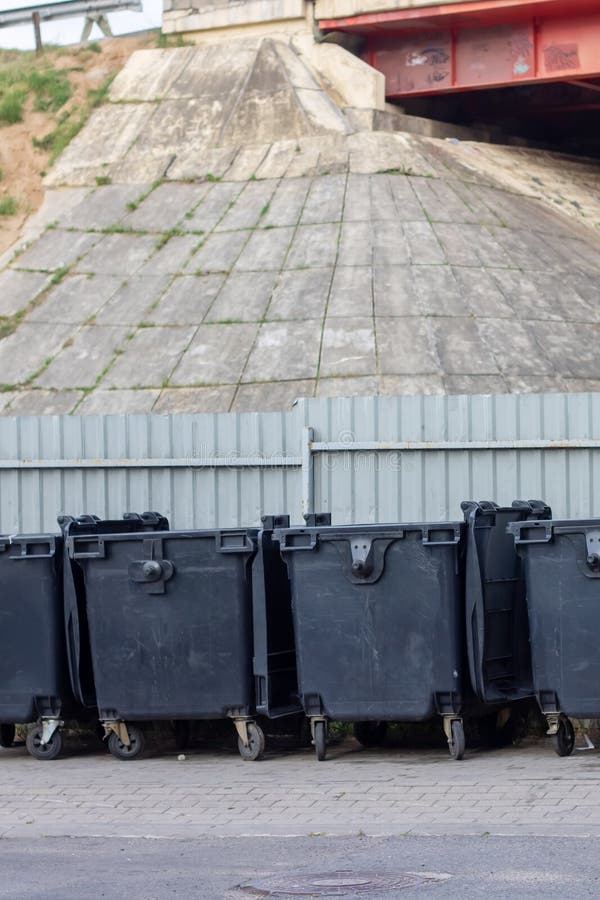 A Line of Black Trash Bins is Arranged in Front of a Barrier Stock ...
