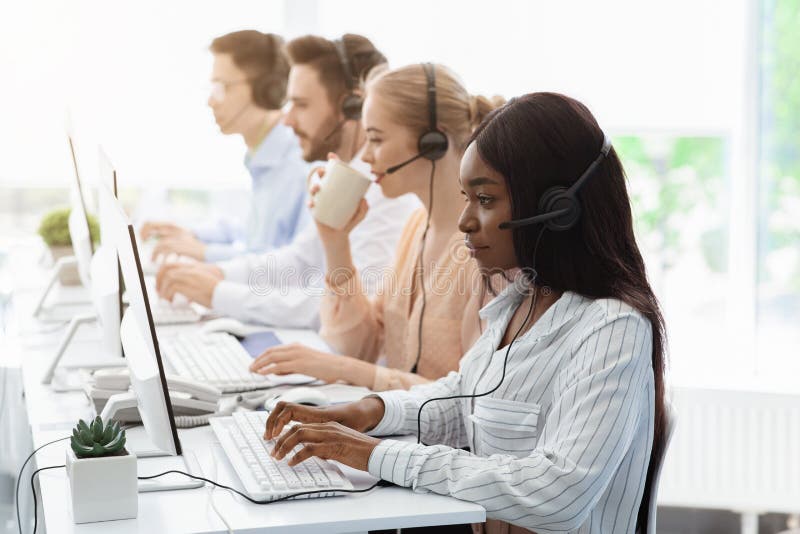 Line of Call Centre Employees with Headphones Working on Computers in ... Line of Call Centre Employees with Headphones Working on Computers in ...
