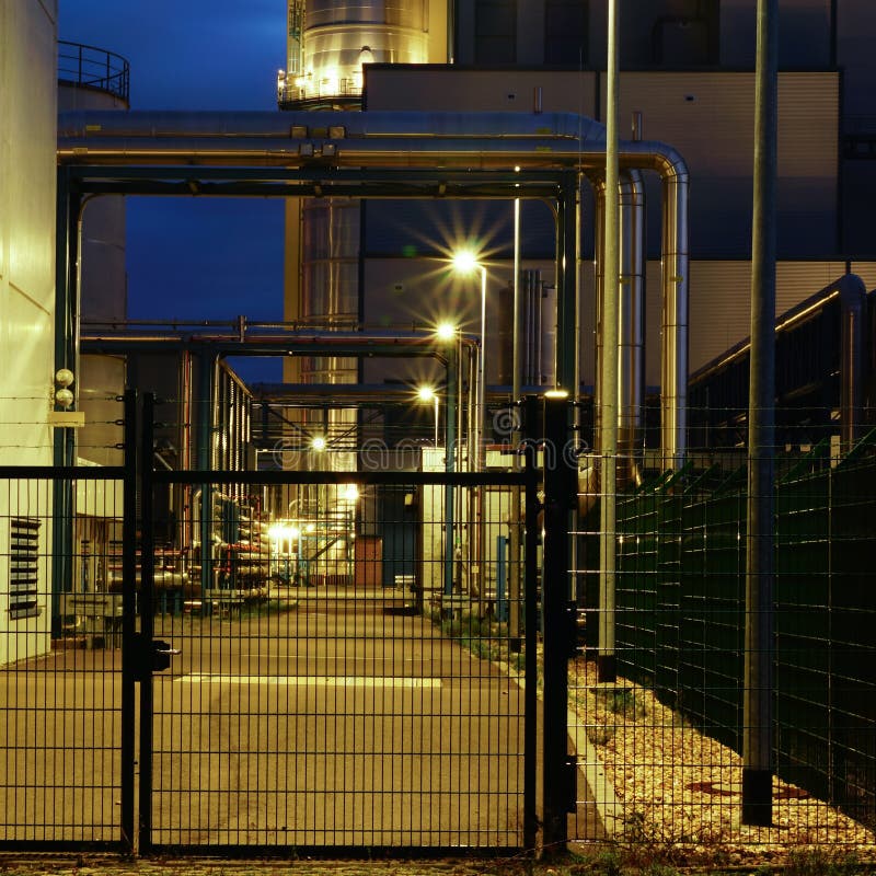 Line of Lit Lamp Posts on an Alley Behind a Locked Gate Stock Photo ...