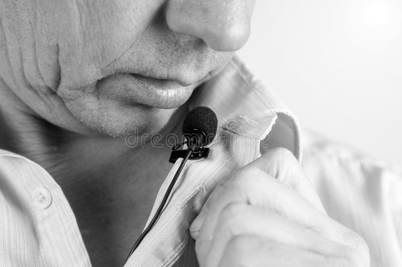 The Man Speaks into a Small Microphone in a Low Voice. Stock Photo ...