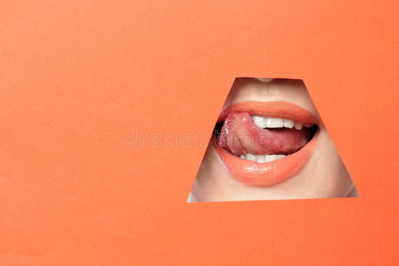 Lips Of Young Woman With Beautiful Lipstick Visible Through Hole In Color Paper Stock Image