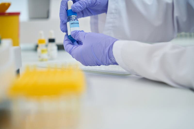 Liquid in a Bottle with a Blue Cap in the Hands of a Laboratory ...