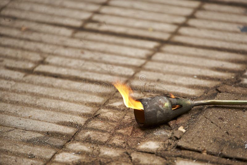 Lit Blowtorch, Throwing Fire Leaning on the Ground. Composition with ...