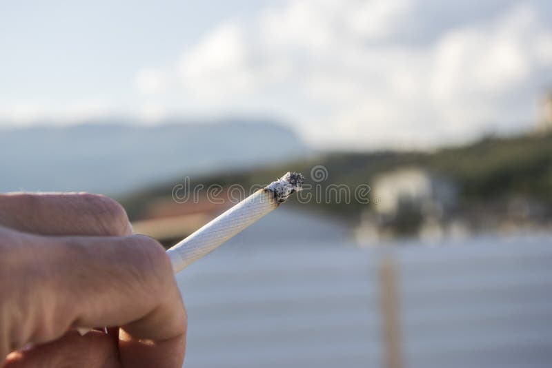 Lit cigarette in hand stock photo. Image of burning - 236337332