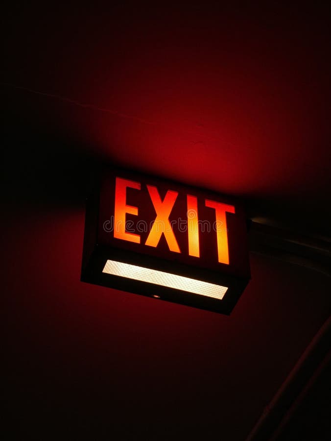 A Lit Exit Sign in the Dark Next To a Wall Stock Photo - Image of ...