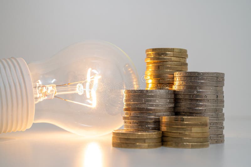 Lit Light Bulb with Coins beside it. Energy Tariffs Increase. Stock ...
