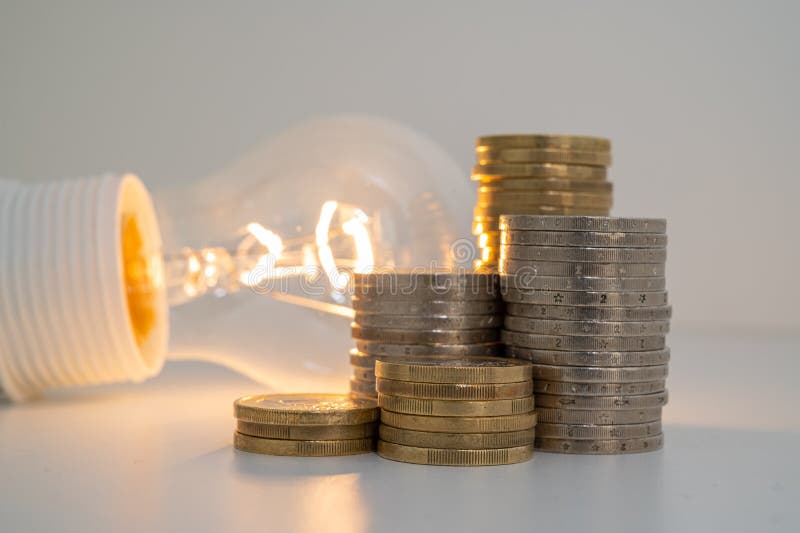 Lit Light Bulb with Coins beside it. Energy Tariffs Increase. Stock ...