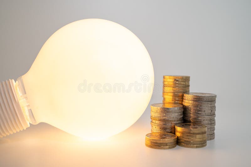 Lit Light Bulb with Coins beside it. Energy Tariffs Increase. Stock ...