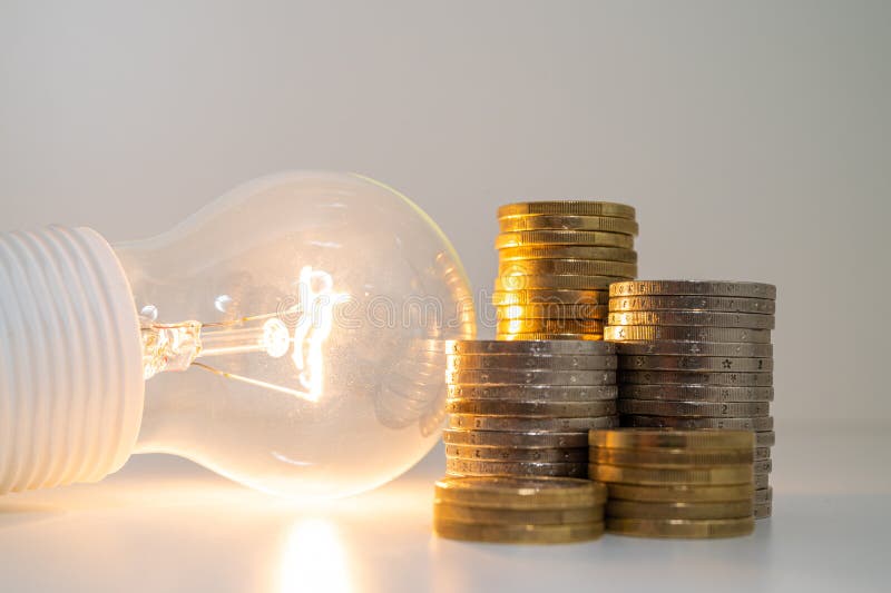 Lit Light Bulb with Coins beside it. Energy Tariffs Increase. Stock ...