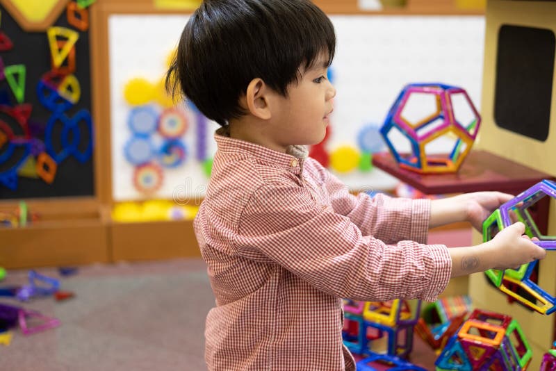 A Little Asian Boy is Playing with a Square Magnetic Puzzle Stock Image ...